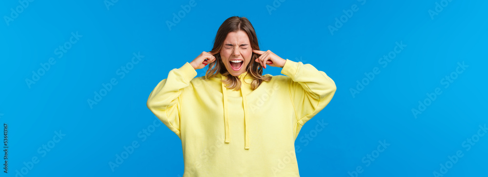 Annoyed and disturbed bothered blond woman shut ears and scream as hear ...