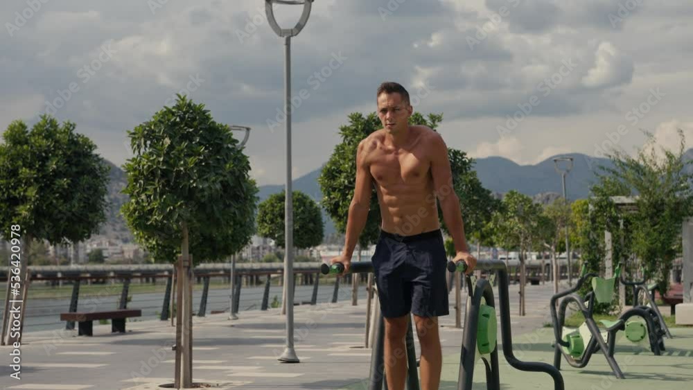 Man flexing abs on parallel bars in gym. Working on his core. Full ...
