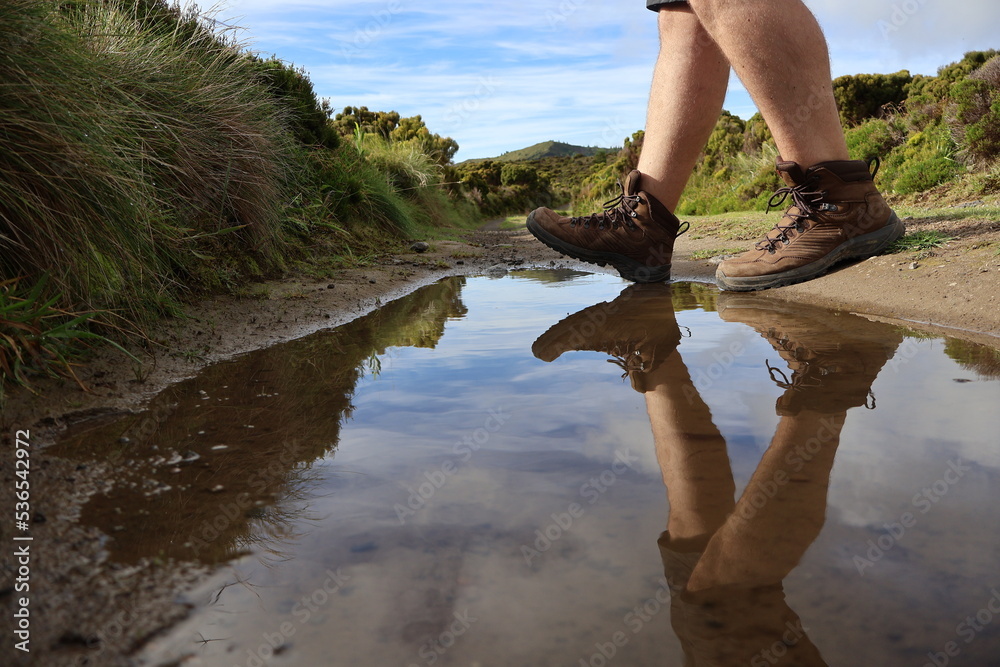 Un homme en randonnée marche dans une flaque d'eau boueuse à la ...