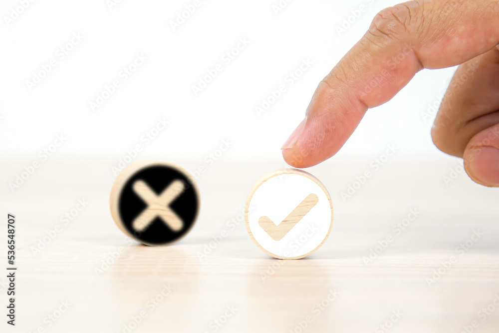 Hand choose check mark on wooden toy with cross symbol for true or ...