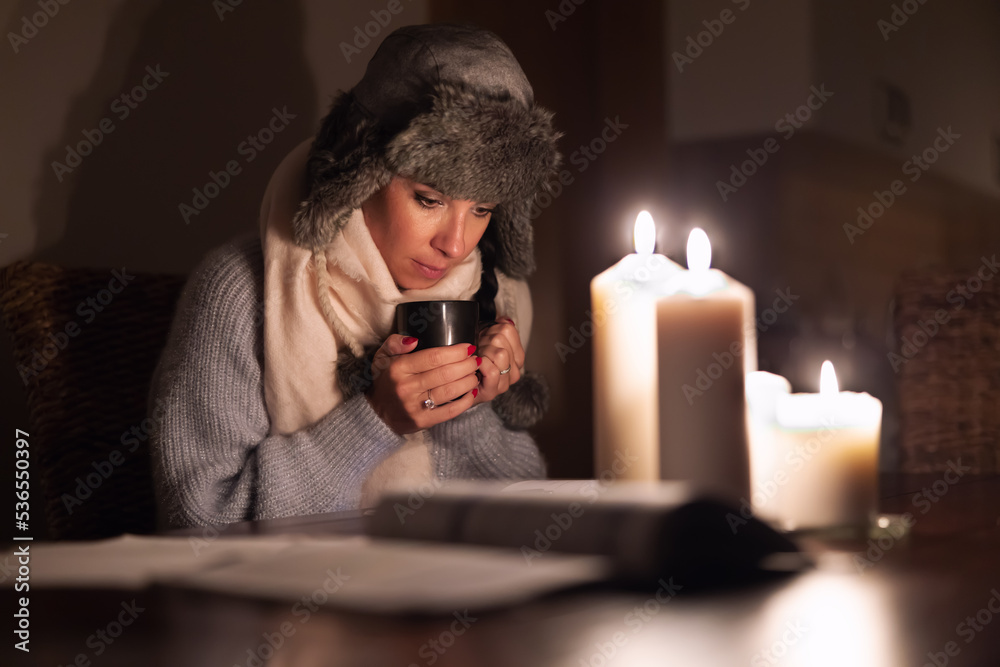 Freezing young woman in winter clothes warms her hands on cup of tea ...