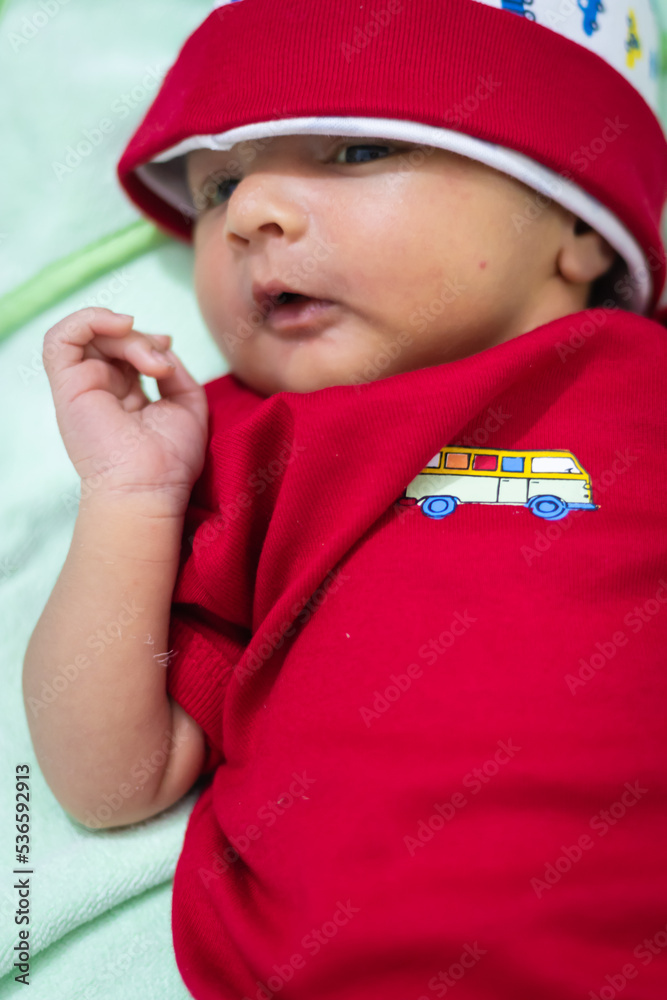 cute newborn baby looking at camera in red dress from different angle ...