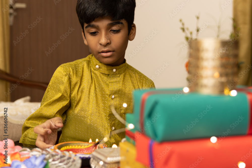 Young boy, kid, dressed up in ethnic lighting diya or lamp with smile ...
