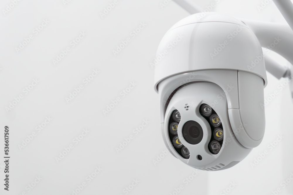 Round CCTV camera with antennas shoots video on the white wall. Digital ...