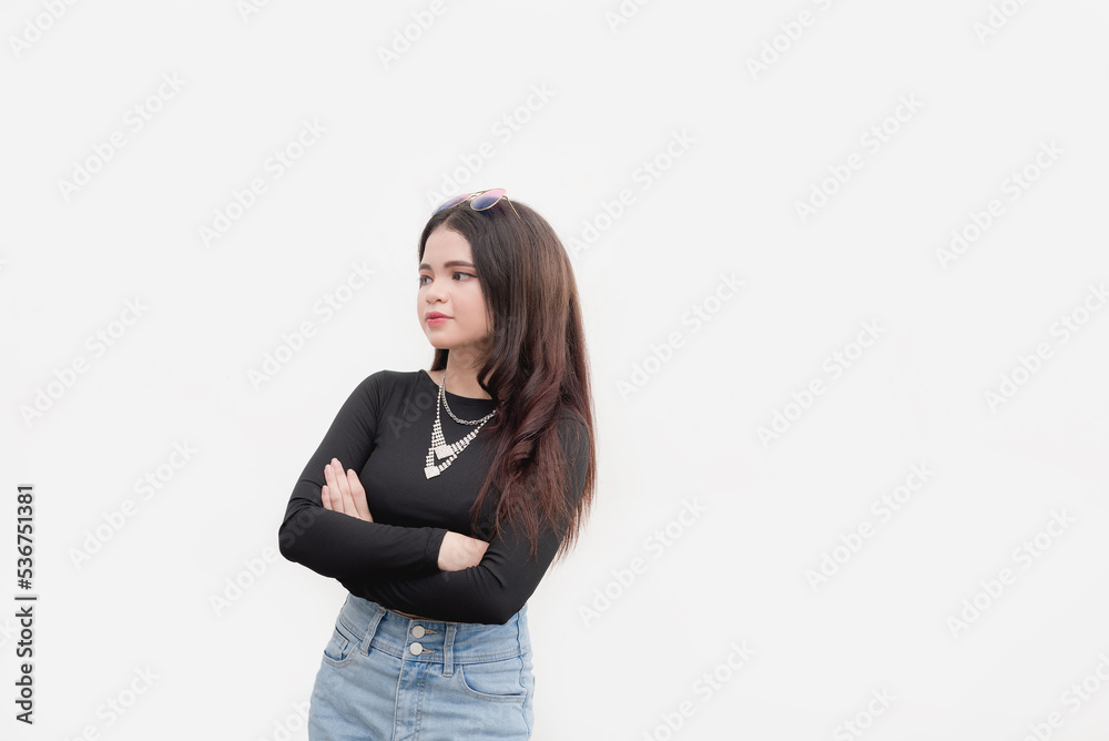 An annoyed young woman crosses her arms while doing a side view pose ...