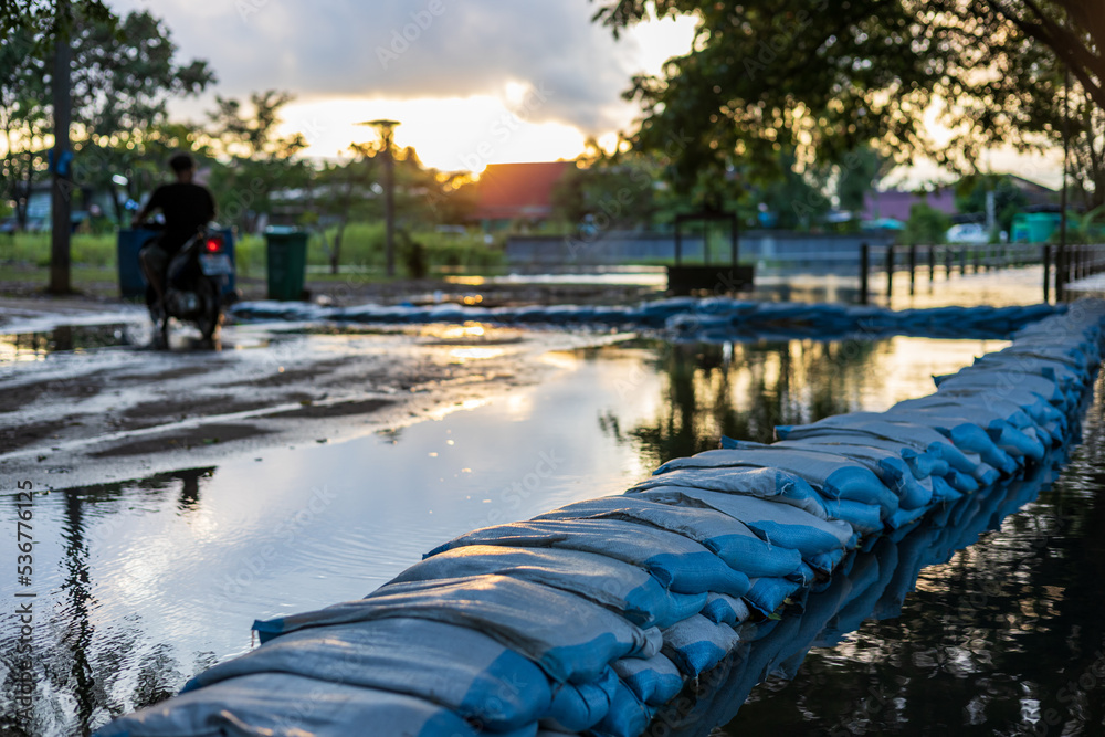 Blue sacks filled with sand are stacked in rows to form dams to prevent ...