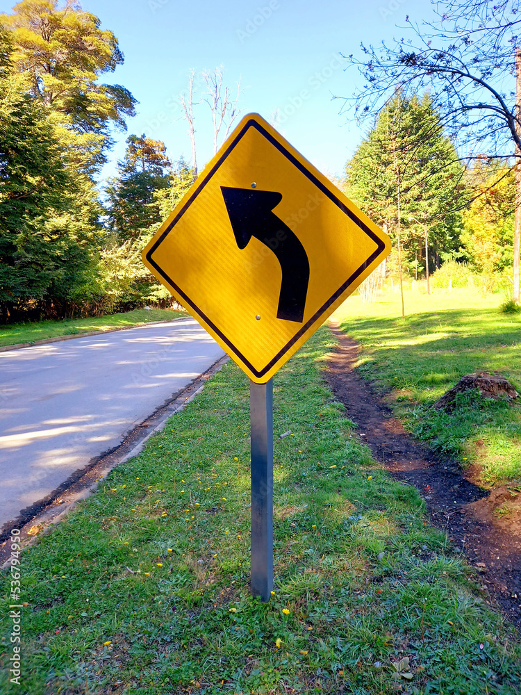 Informative yellow traffic signal with a black arrow indicating a curve ...