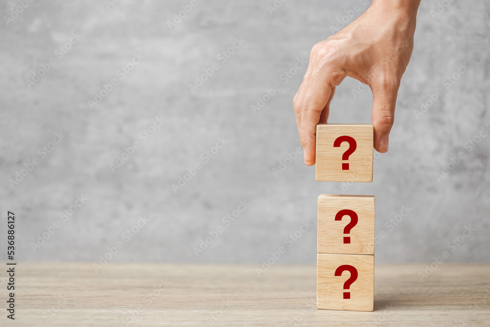 hand holding Questions Mark ( ? ) on cube block on table. FAQ ...