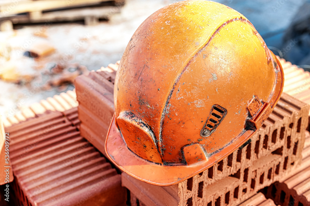 An orange hard hat or helmet for a worker lies on the bricks. Safety in ...