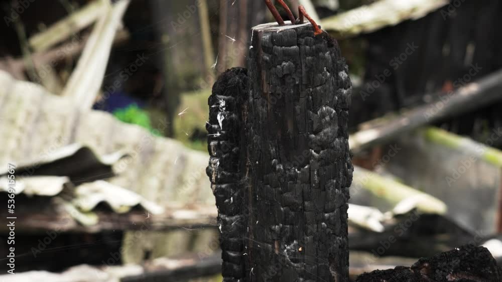 Black burnt log with rusty bent nails of a house burned by fire. Wood ...