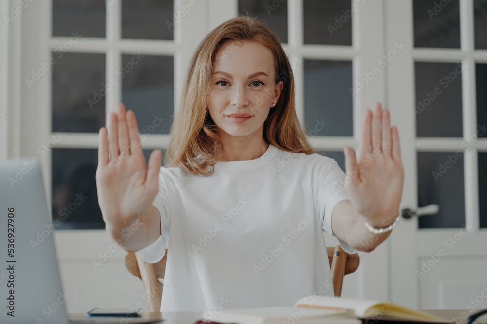 Serious young female showing stop gesture by palms, saying no to gender ...