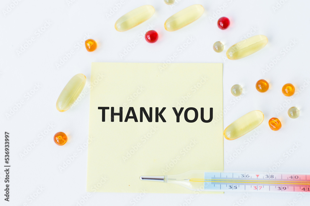 Thank you text on a yellow card on a white background next to scattered ...