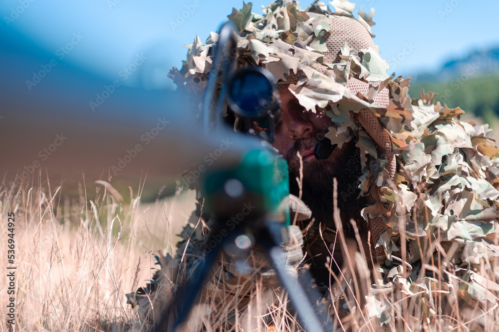army soldier holding sniper rifle with scope and aiming in forest. war ...