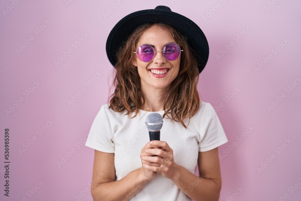 Beautiful brunette woman singing song using microphone smiling with a ...