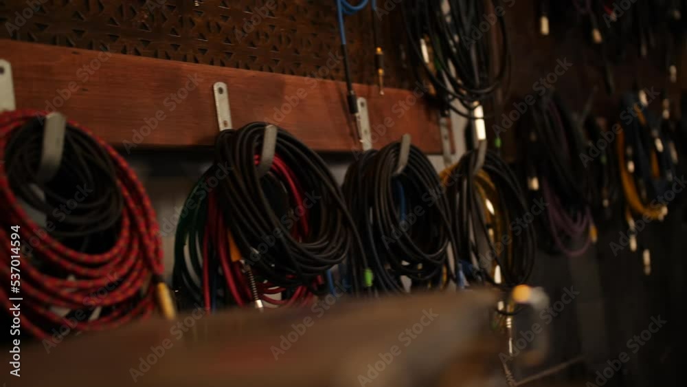 Wires and cables for musical instruments hang on the wall in an analog ...