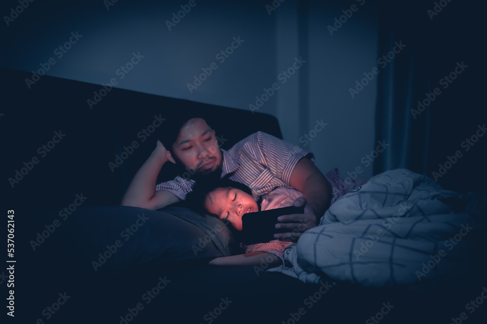 Foto de Dad and daughter sleep on the bed in bedroom,Watch cartoon with ...