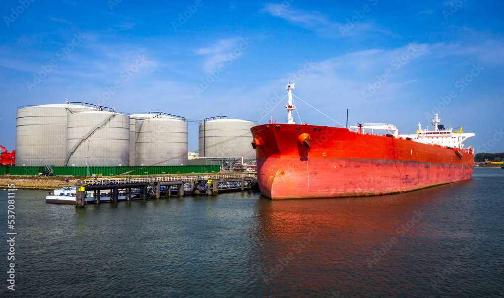 Crude oil tanker docked at a oil storage silo terminal in the port ...