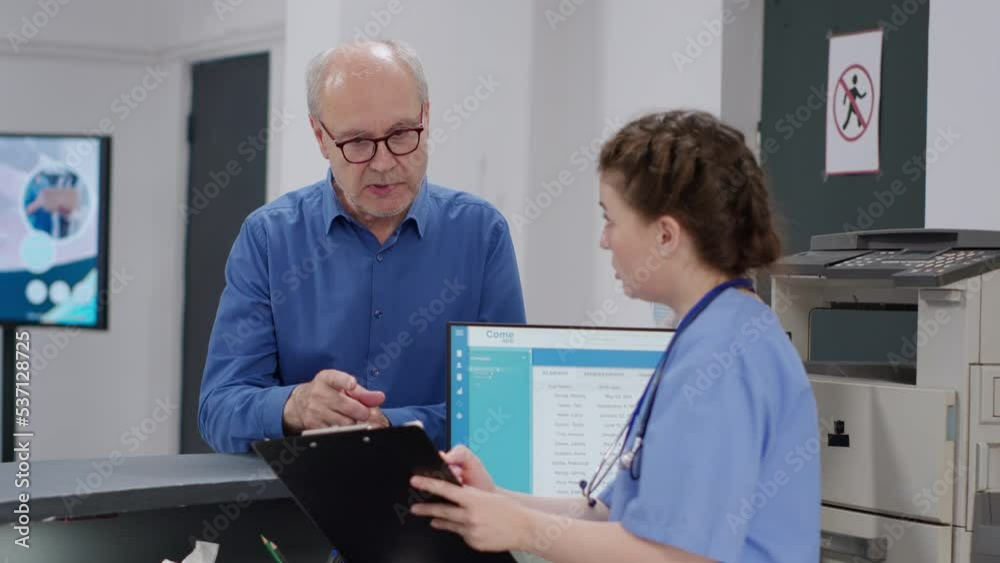 Medical assistant and old patient filling in checkup report papers at ...