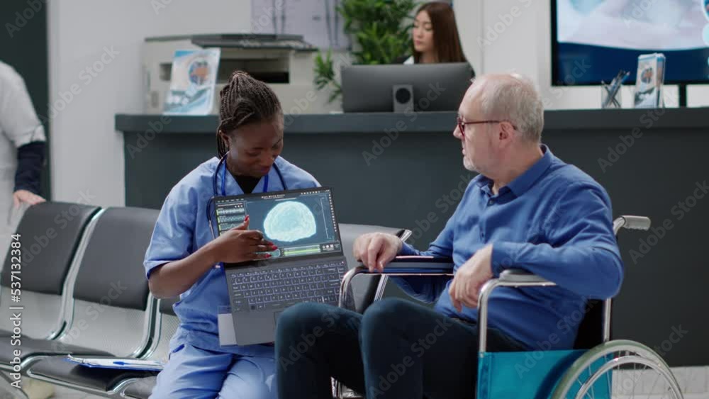 Nurse showing brain tomography to man with physical disability, doing ...