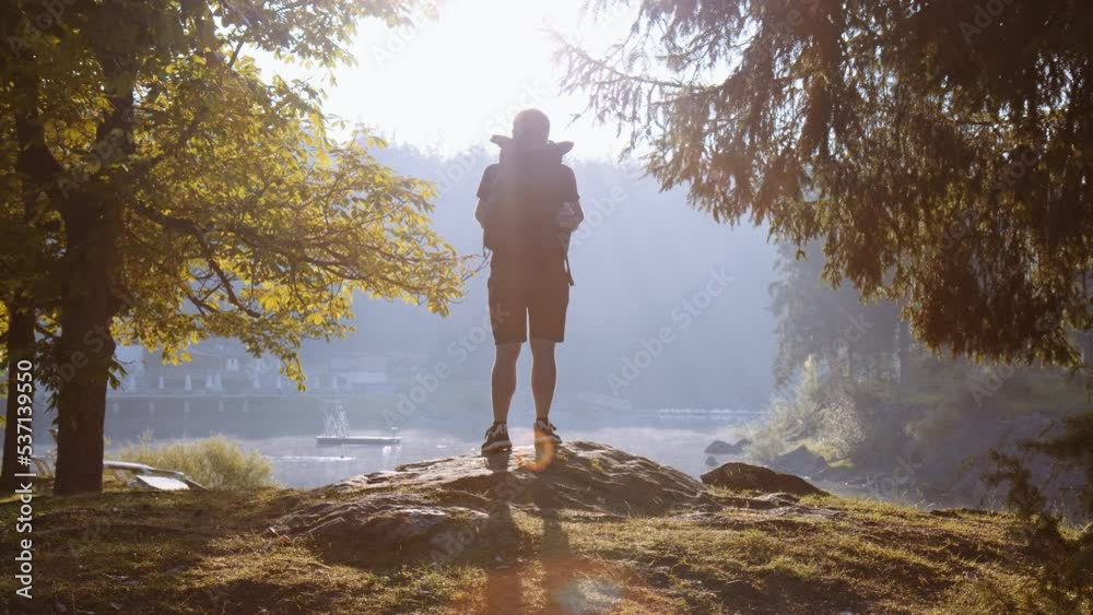 Tourist Hiker Hiking Standing Alone on Lakefront Rocks Looking at Lake ...