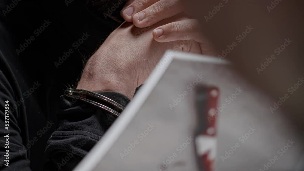 Detained criminal in handcuffs, close up. Police interrogation. Detective shows to murderer ...