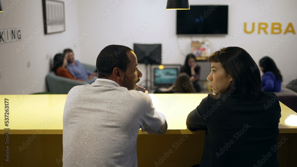 People conversing at workplace. Two diversed work colleagues talking at ...