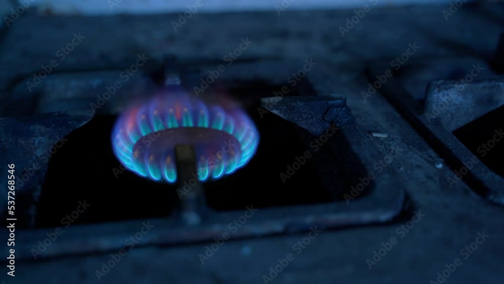 A blue flame burns unsteadily in a gas cooker at a cold color ...