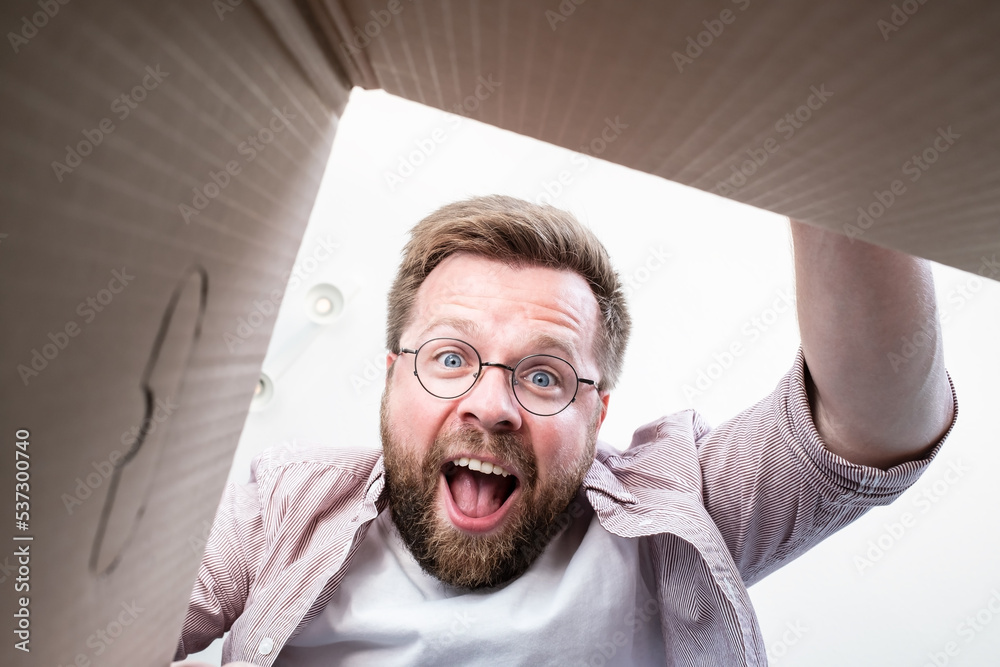 Man with glasses unpacked the delivered box with a parcel, looks at the ...