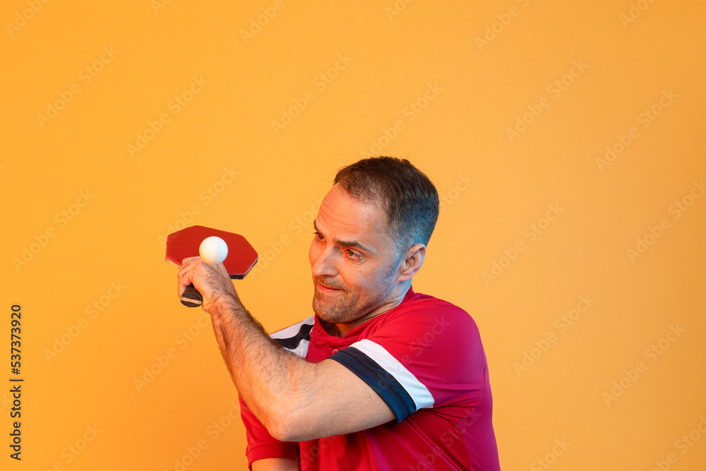 Man plays table tennis on yellow studio background. Professional player ...