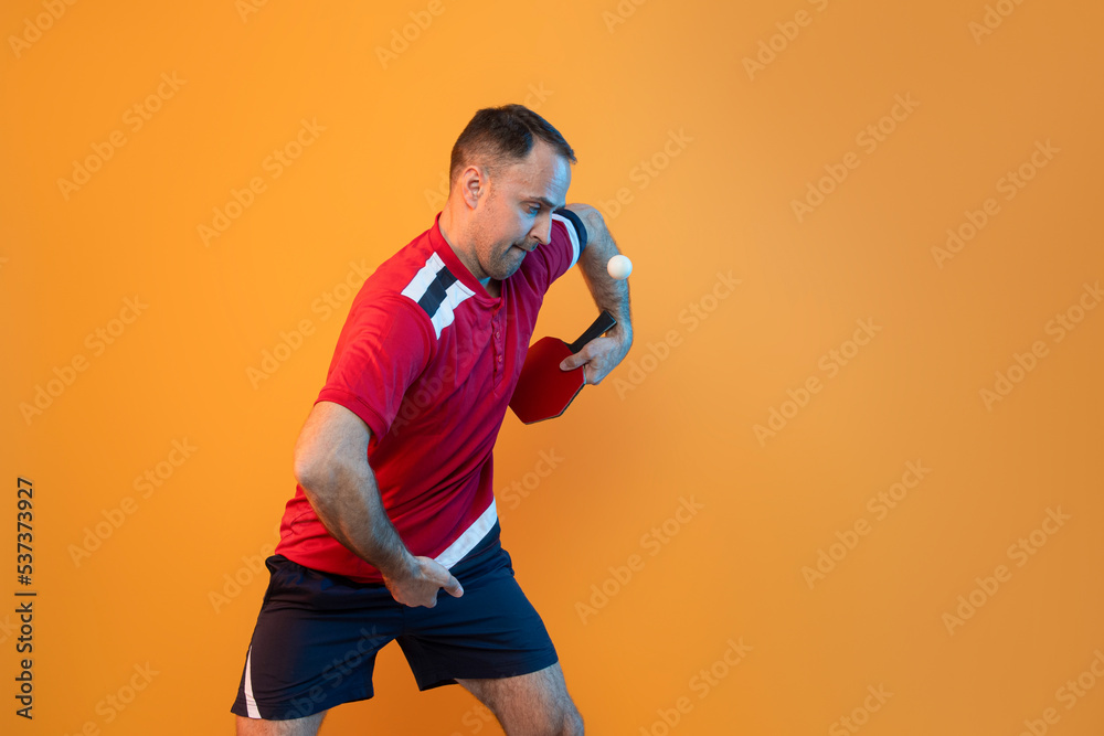 Man plays table tennis on yellow studio background. Professional player ...