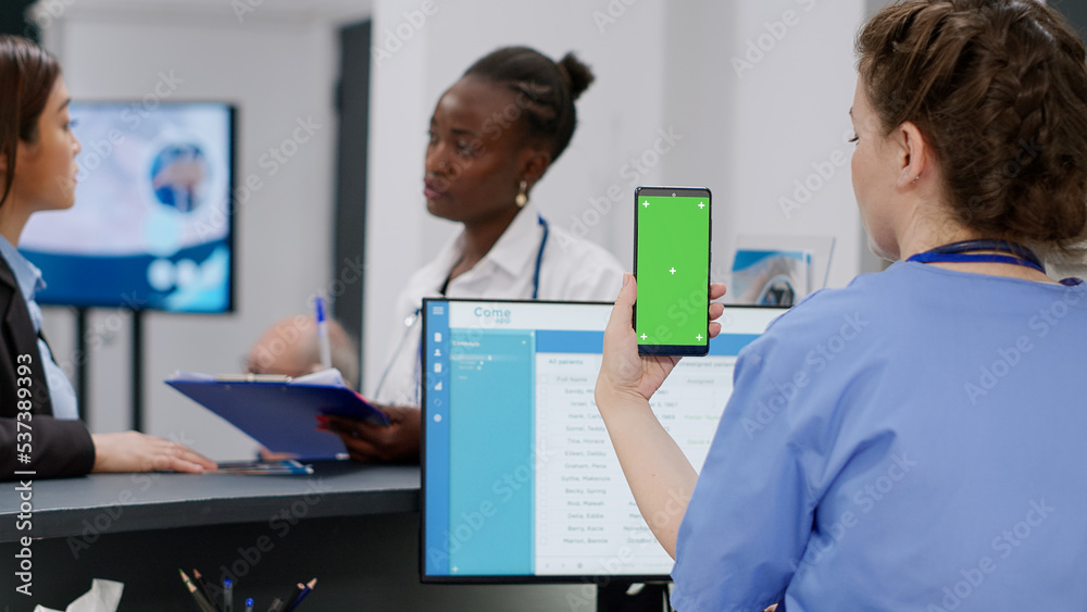 Medical assistant holding smartphone with greenscreen display at ...