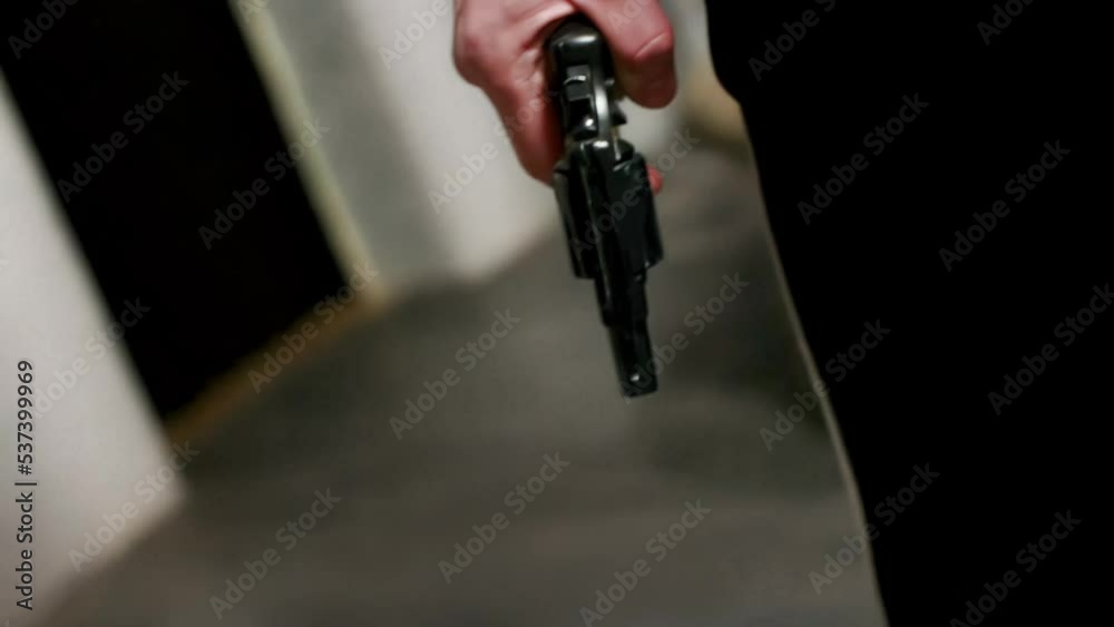 Close-up Man lowers his revolver pistol to the foot in black pants ...