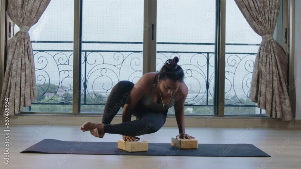 Young fit Indian Asian Woman or female performing an advanced yoga hand ...