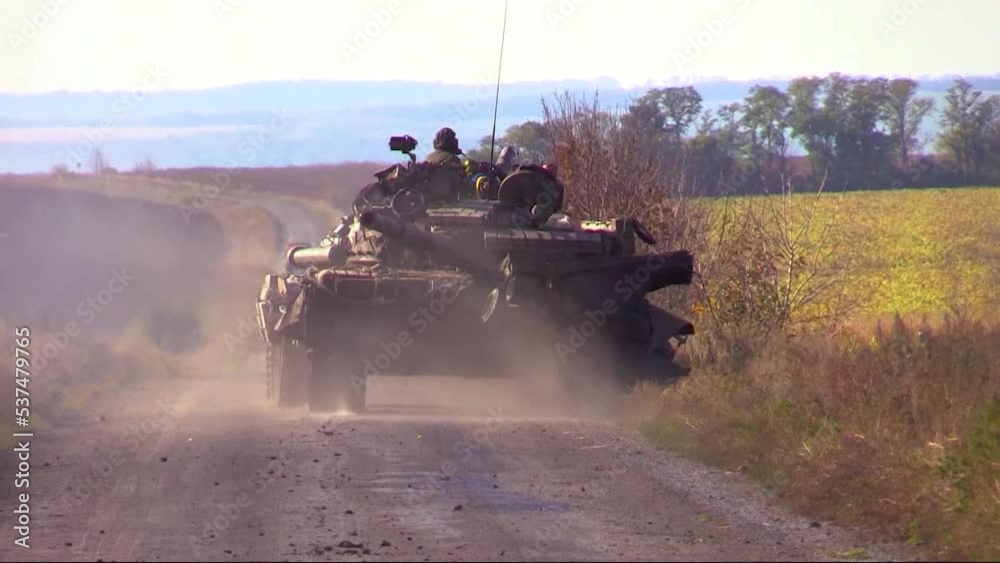 A Ukrainian tank drives along the road between the fields ...