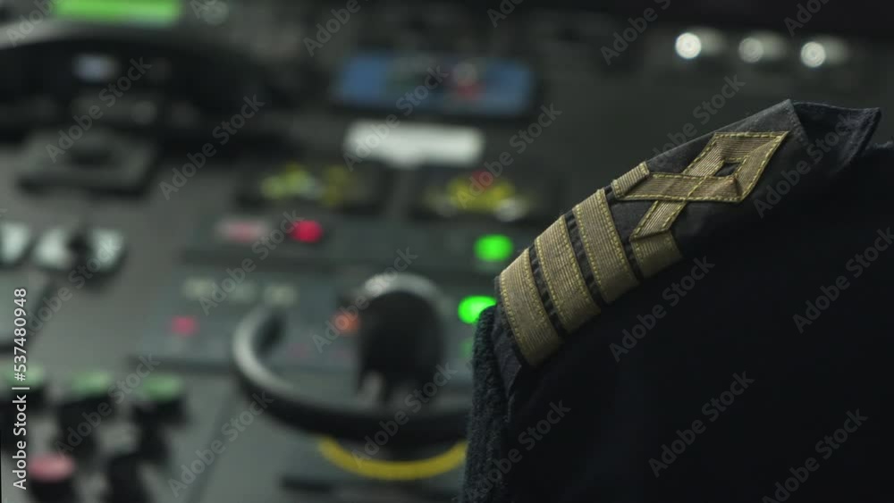 Captain's shoulder strap, control panel of ship on background. Green ...