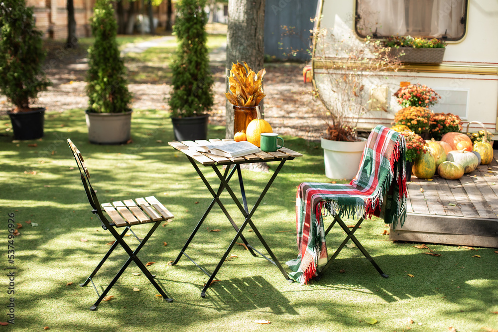 Interior cozy campsite with flowers and pumpkins. Wooden RV house porch ...