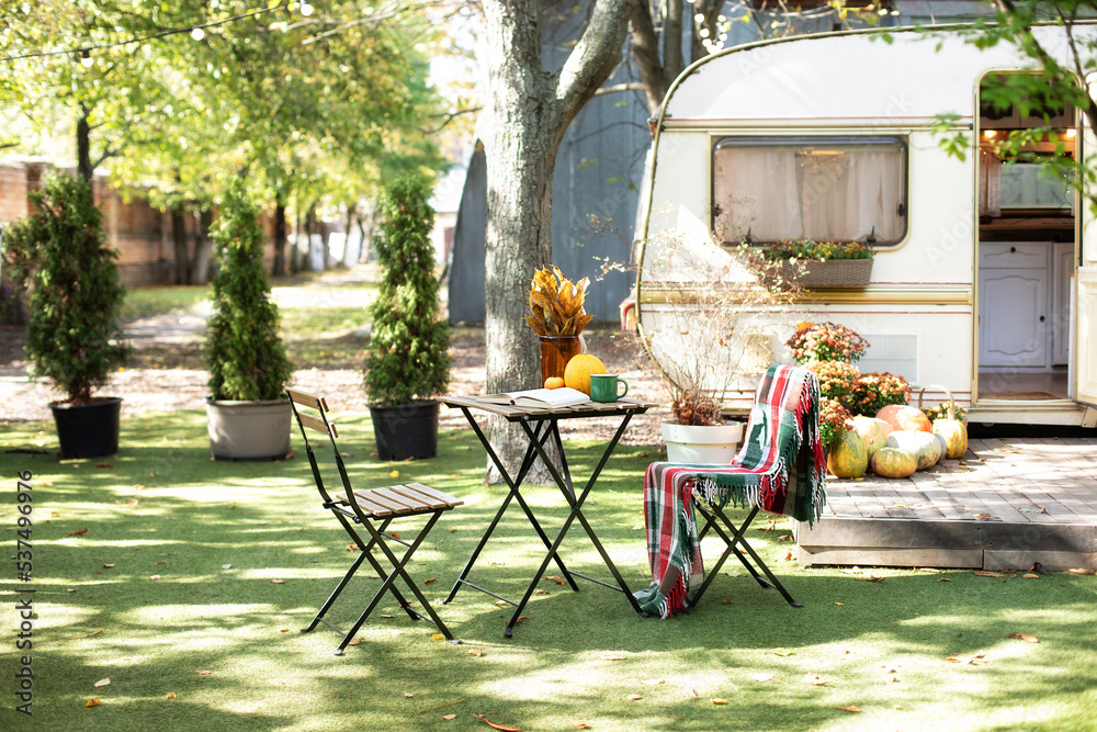Interior cozy campsite with flowers and pumpkins. Wooden RV house porch ...
