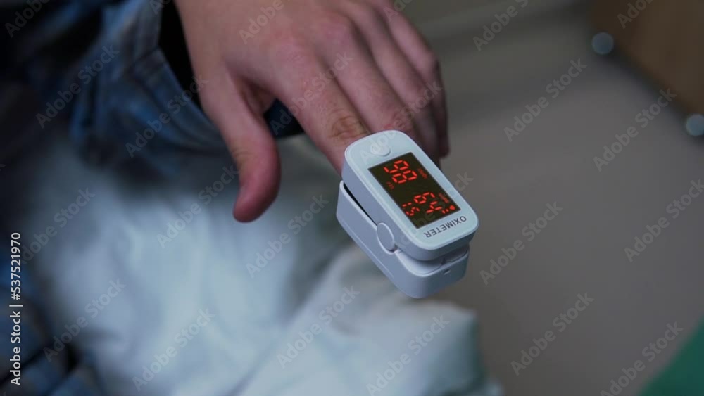 Doctor in green uniform attaches pulse oximeter on finger of patient ...