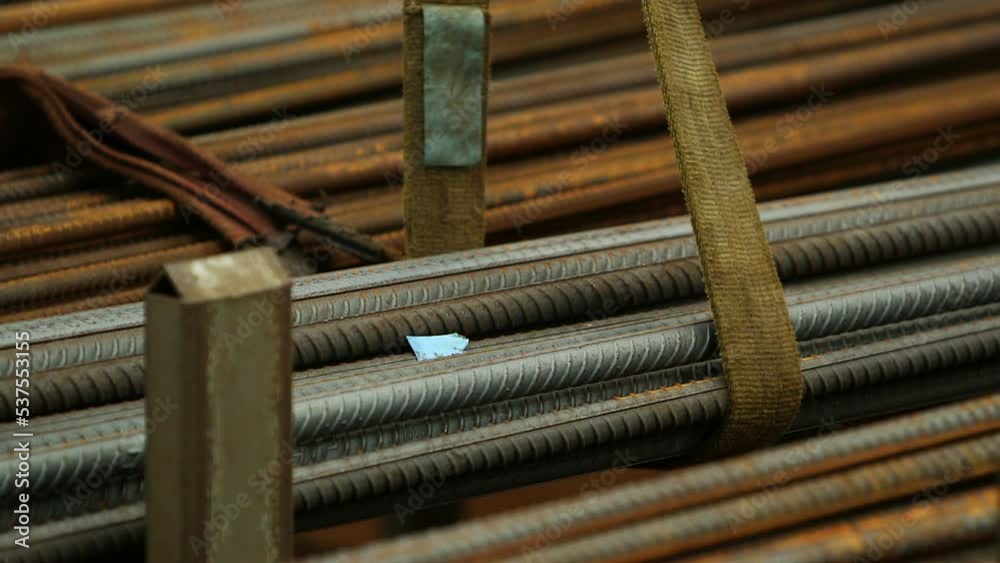 A stack of steel bars is being lowered down. A glimpse of a person ...