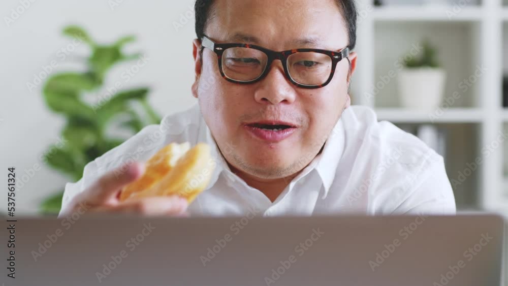Asian fat man eating donut, sweet, junk food during working with ...