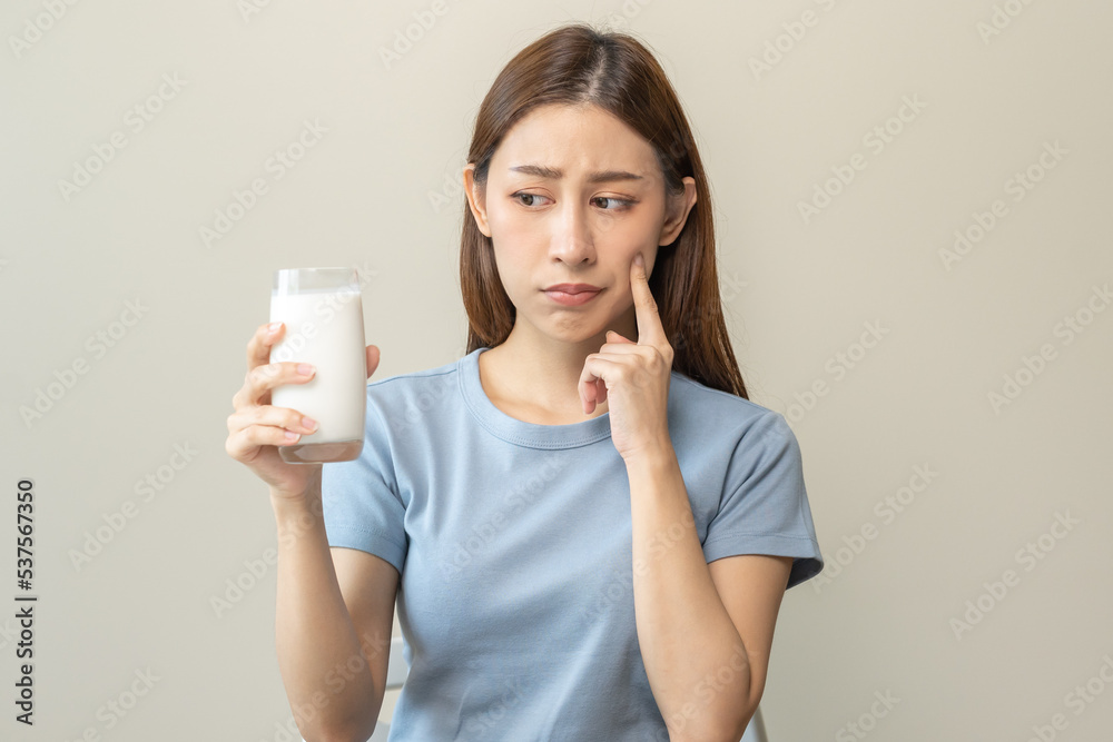 Allergy asian young woman, girl looking, holding glass of milk, face in ...