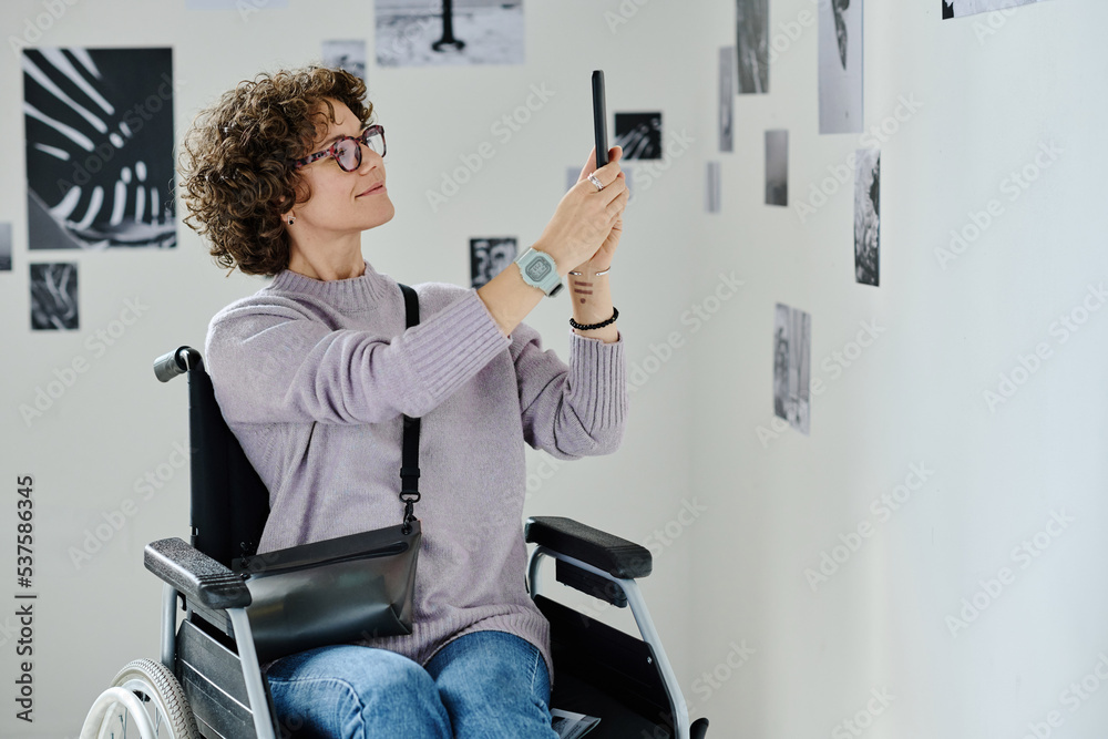oung woman with disability photographing pictures on wall on her ...