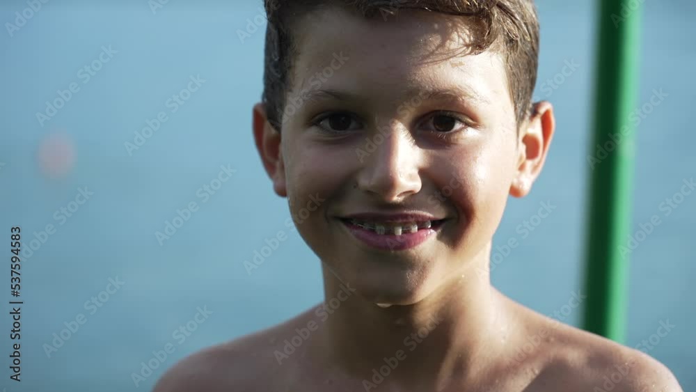 Wet kid standing outside in sunlight smiling with braces. Closeup young ...