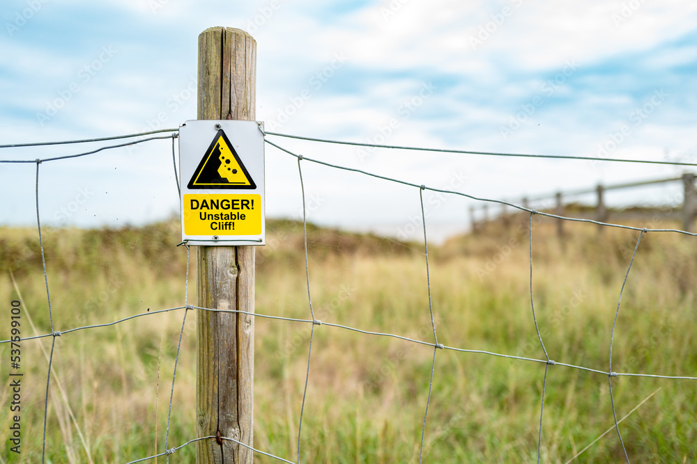 Shallow focus of a boundary fence and yellow warning sign bringing ...