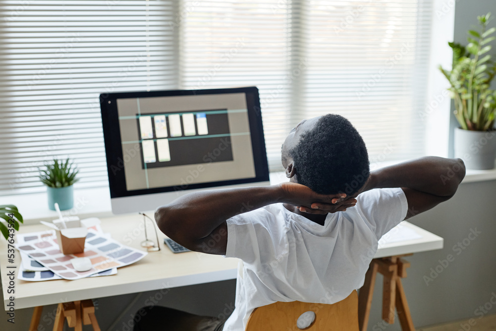 Back view of tired black man stretching muscles at office workplace ...