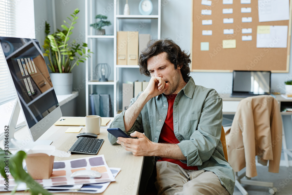 Stockfoto Portrait of Caucasian young man yawning at office workplace ...