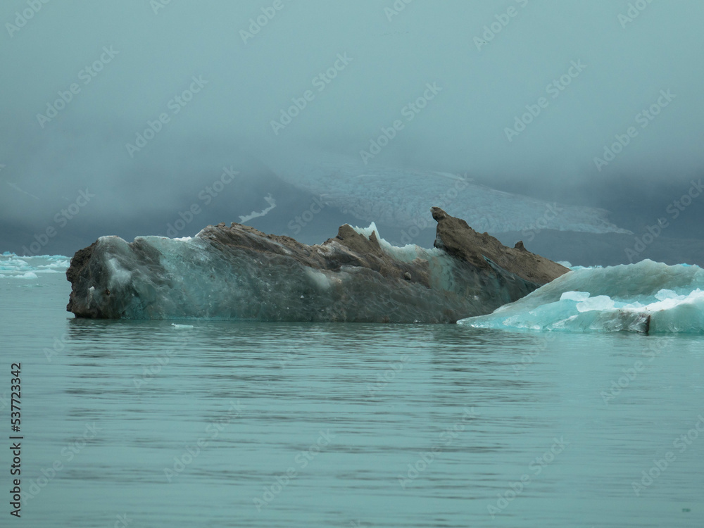 Dirty iceberg with sand and silt floating in the arctic ocean. Severely ...
