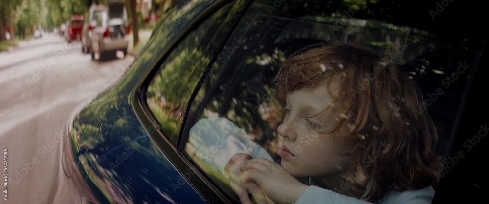 CU Portrait of cute bored little kid boy looking through closed car ...