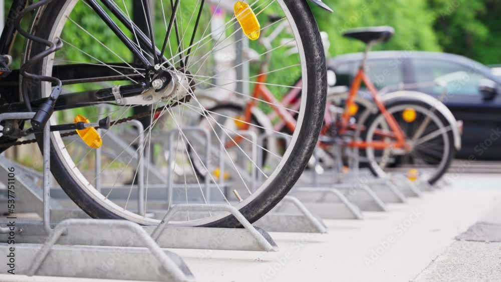 Video Stock Close up on bicycle wheel tied and parked on bike rack next ...