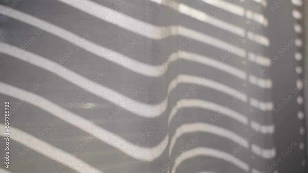 Window shutters or blinds open up creating shadow lines on white ...